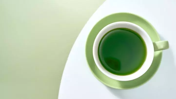 tasse verte et soucoupe de thé vert sur la vue aérienne de la table blanche, sol vert