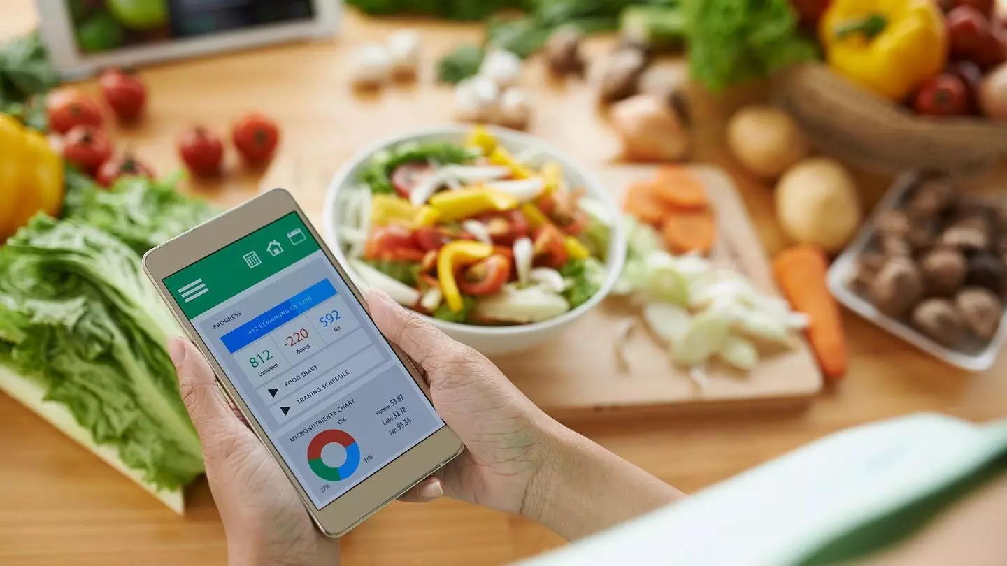 een persoon die de weight watchers-app gebruikt terwijl ze eten bereiden