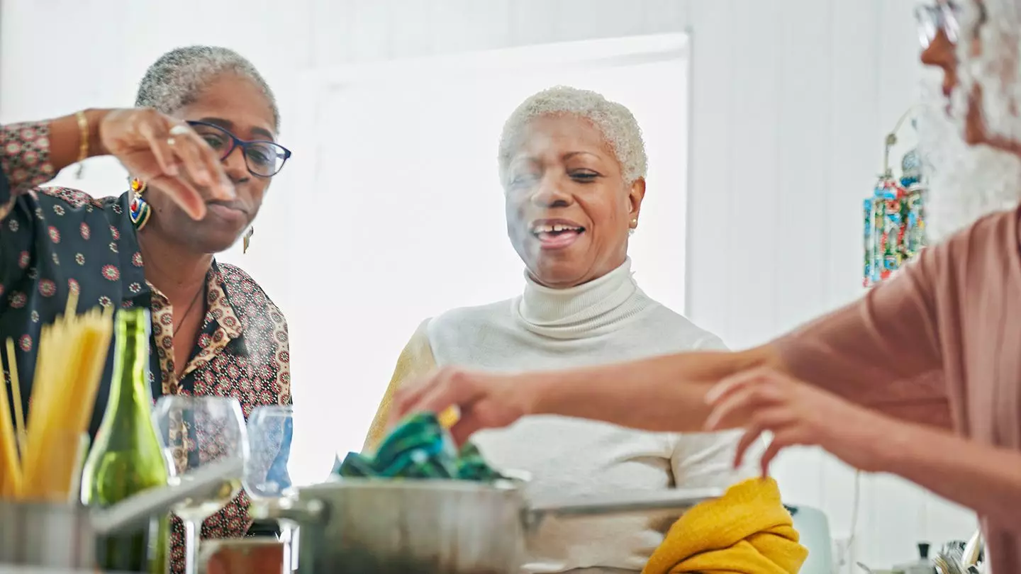 drei reife schwarze afroamerikanerinnen in der küche kochen lachende freunde