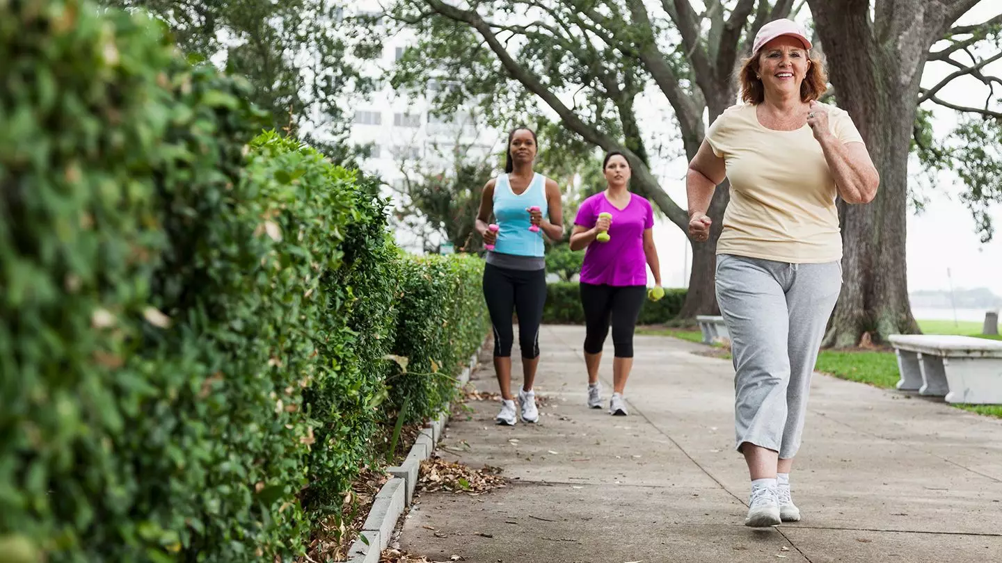 Multi-emulti etnyske froulju oefenje yn park, power walking. Fokus op senior frou 60s op foargrûn.