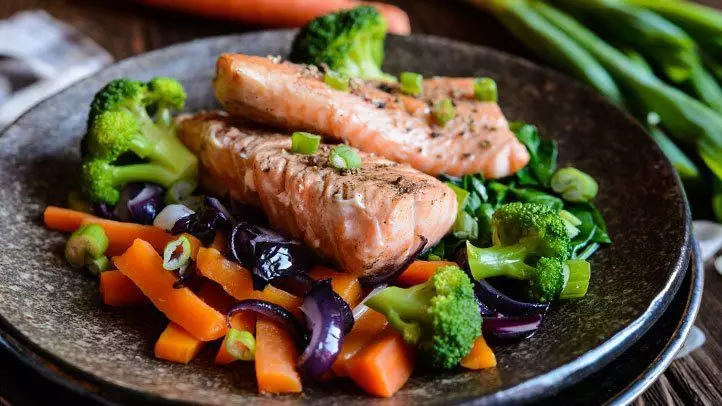 un plato de salmón y verduras que ayudan a seguir una dieta para reducir el reflujo ácido