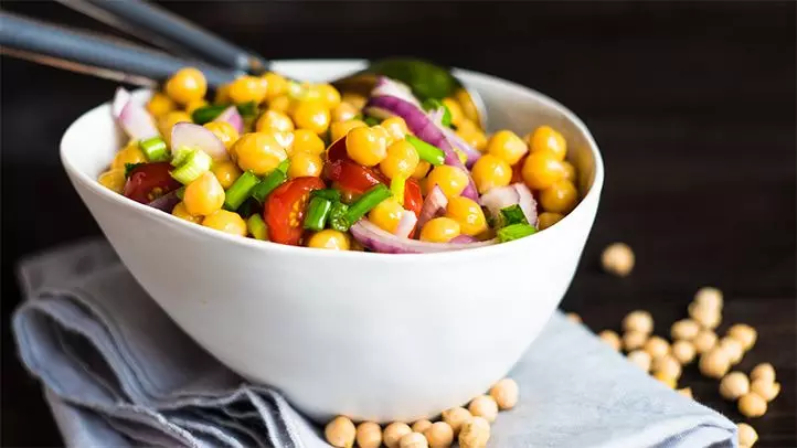 Salata od slanutka sa paradajzom i lukom u beloj posudi