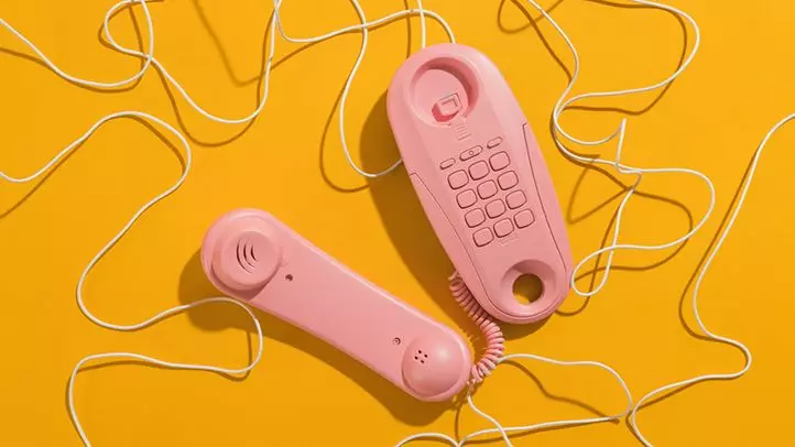 telefono rosa su sfondo giallo con cavo bianco