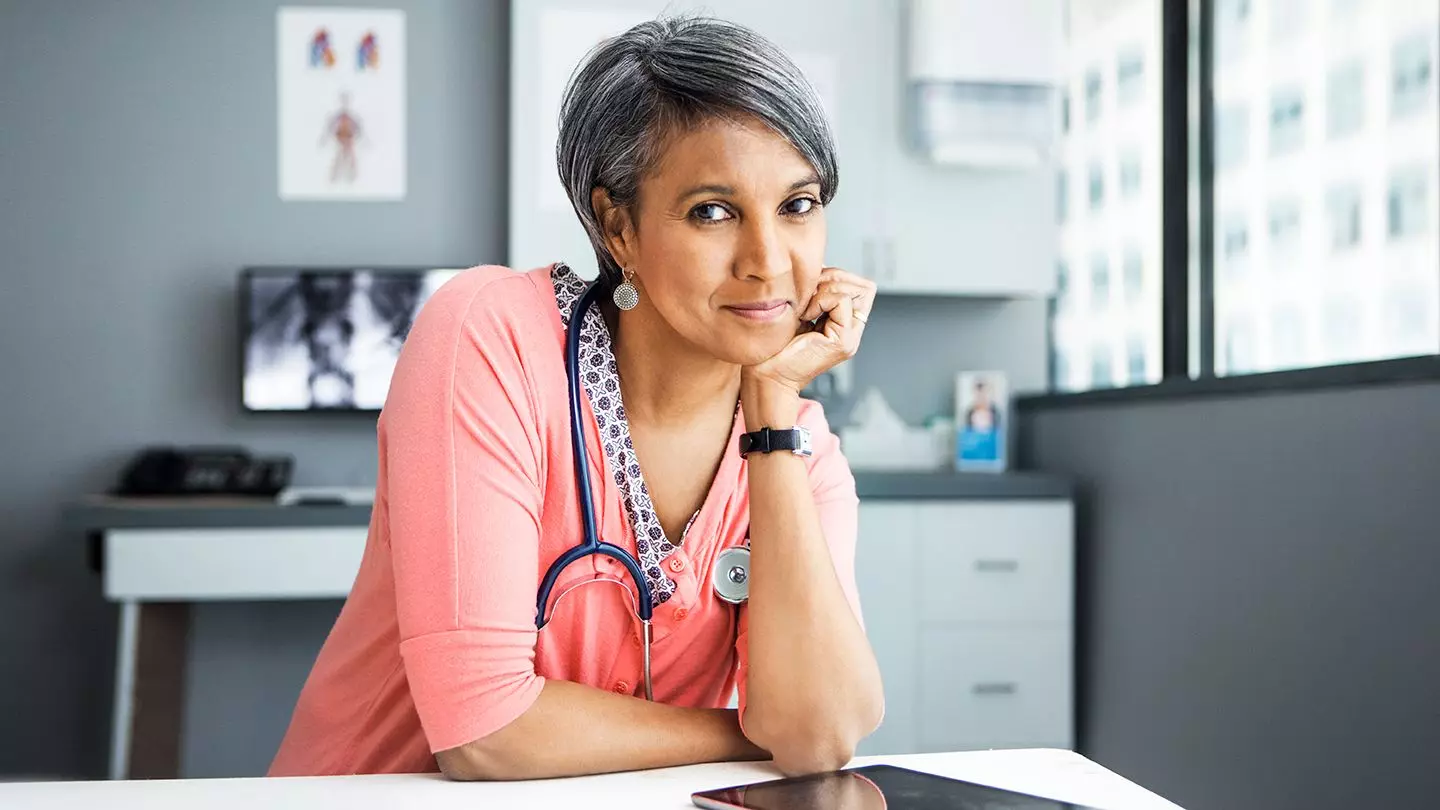 mujer doctora sonriendo en el escritorio en la oficina POC persona negra de color médico afroamericano